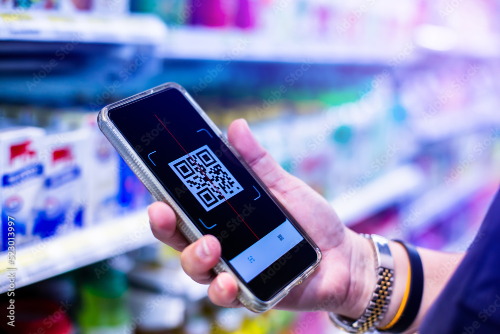 Qr code tag on smartphone with blurry products on shelves in ...