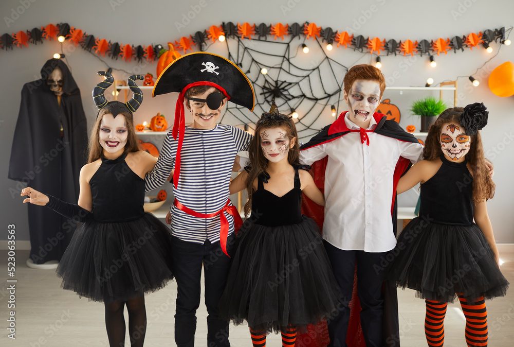 Kids in Halloween costumes. Indoor group portrait of happy friendly ...