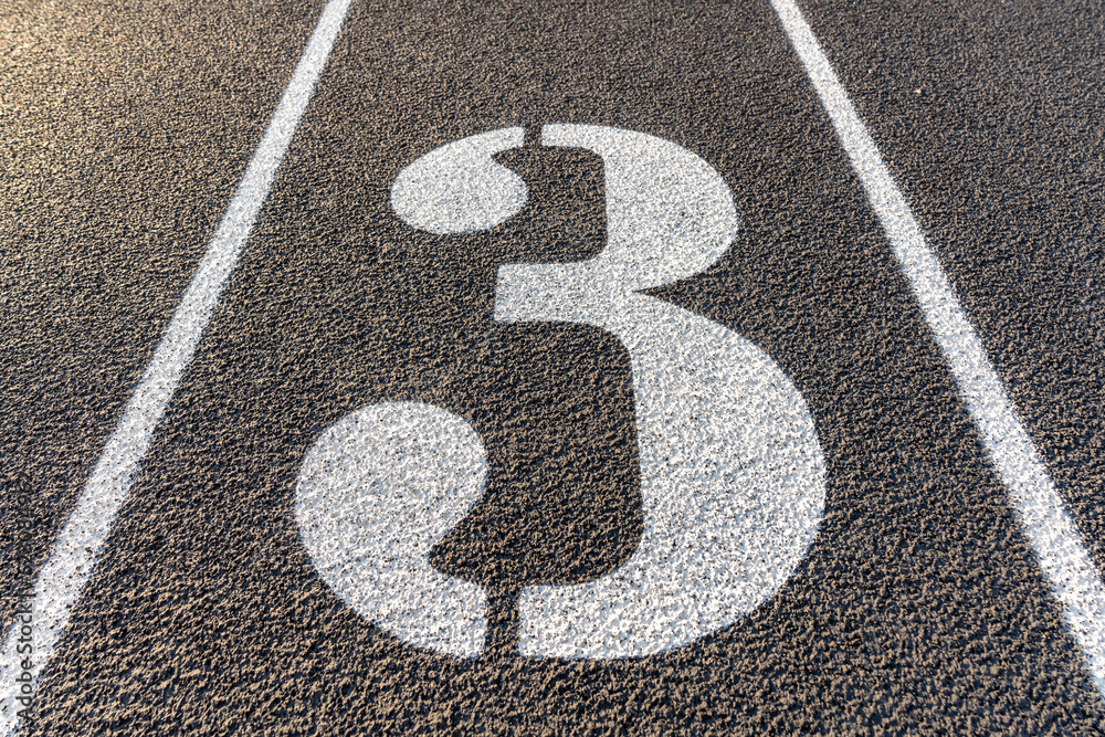 Close up lane number three, 3, on a new black running track with white ...