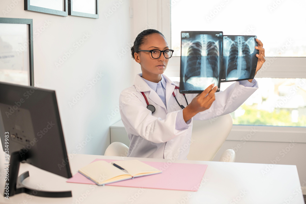 Serious pulmonologist comparing two x-ray pictures of lungs. Young ...
