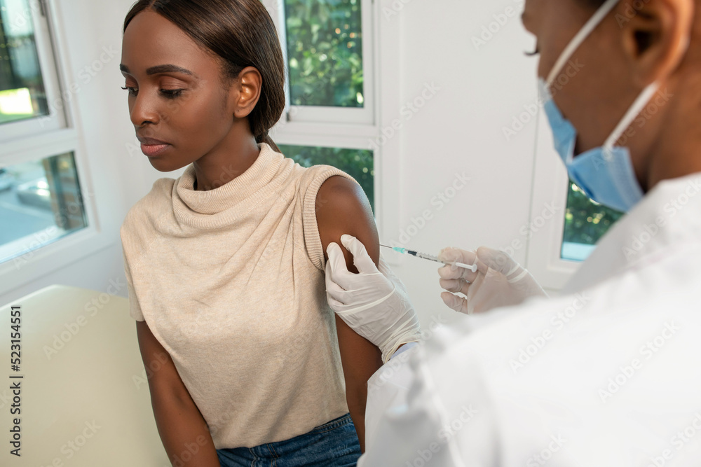 African American woman receiving vaccine shot in clinic. General ...