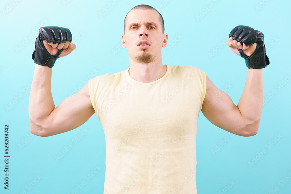 Man in black MMA gloves showing his biceps on a blue background. Boxer ...