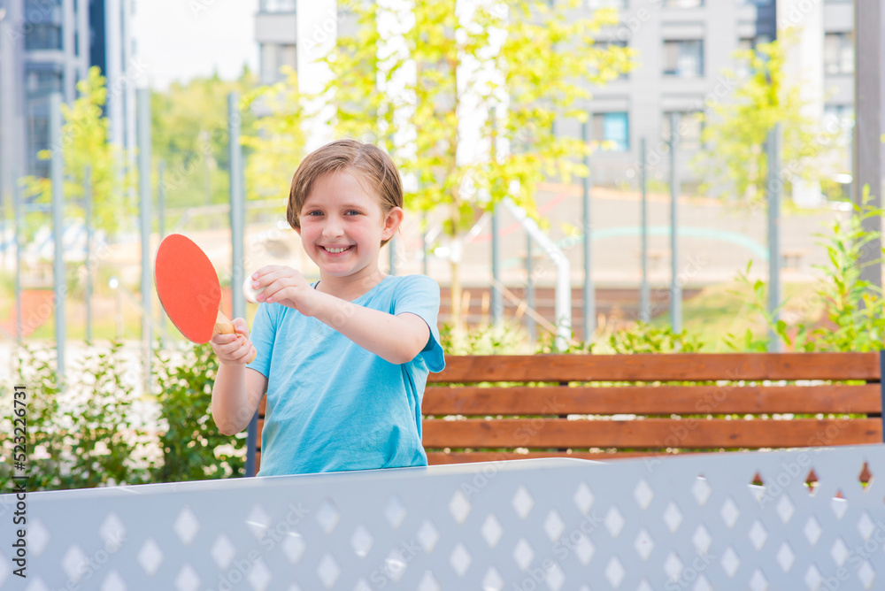 the boy holds a racket and a ball for ping pong and table tennis in his ...
