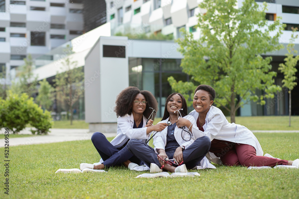 students sitting on the lawn garden reading having fun wearing lab coat ...