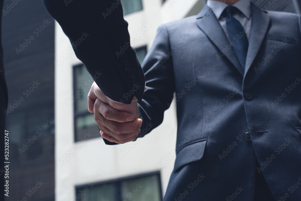Businessmen making handshake with buildings in the city as background ...