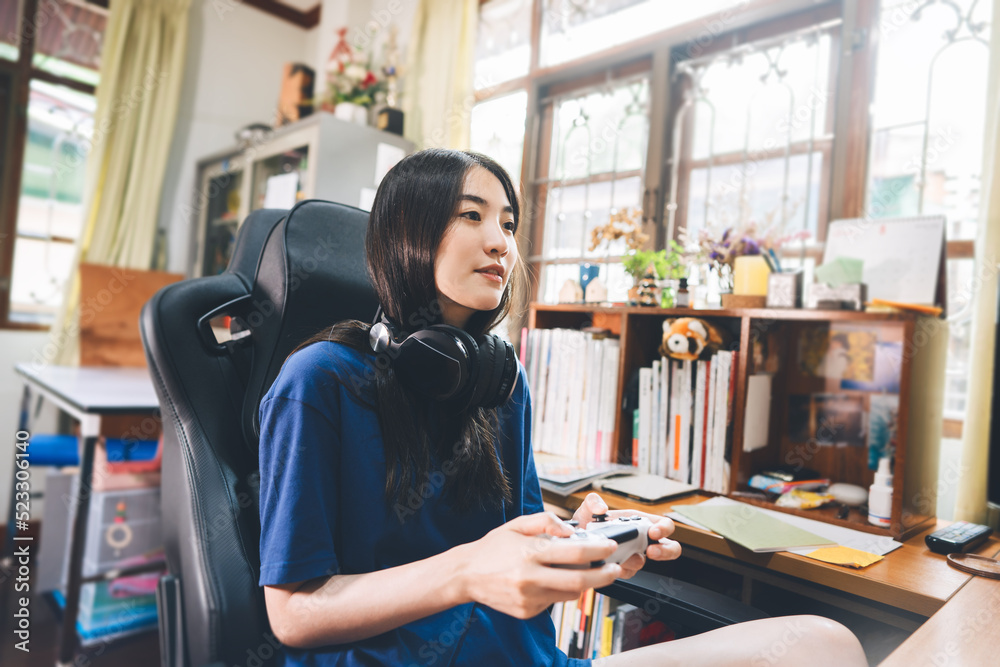 Beautiful young adult asian woman playing a console game at home on ...