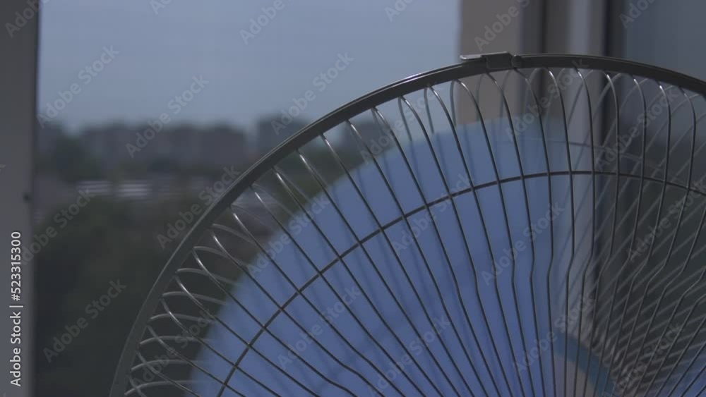 A working air fan stands at a house or apartment window. Background ...