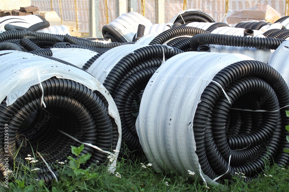 Rolled up pile of twisted, high pressure flexible black rubber pvc ...