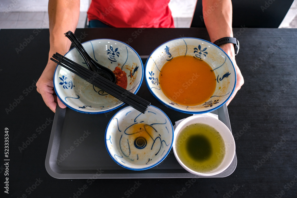 Foto de Man clearing tray of used crockery after dining. Diners at ...