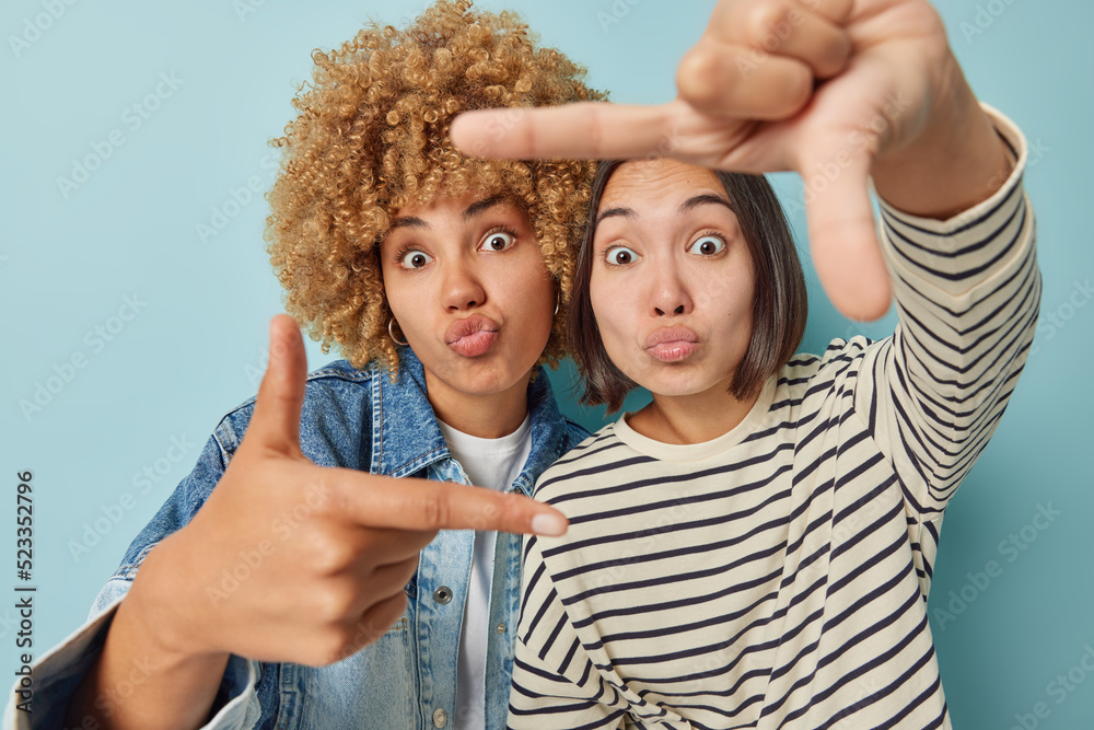 Funny surprised diverse female friends make frame gesture look through ...