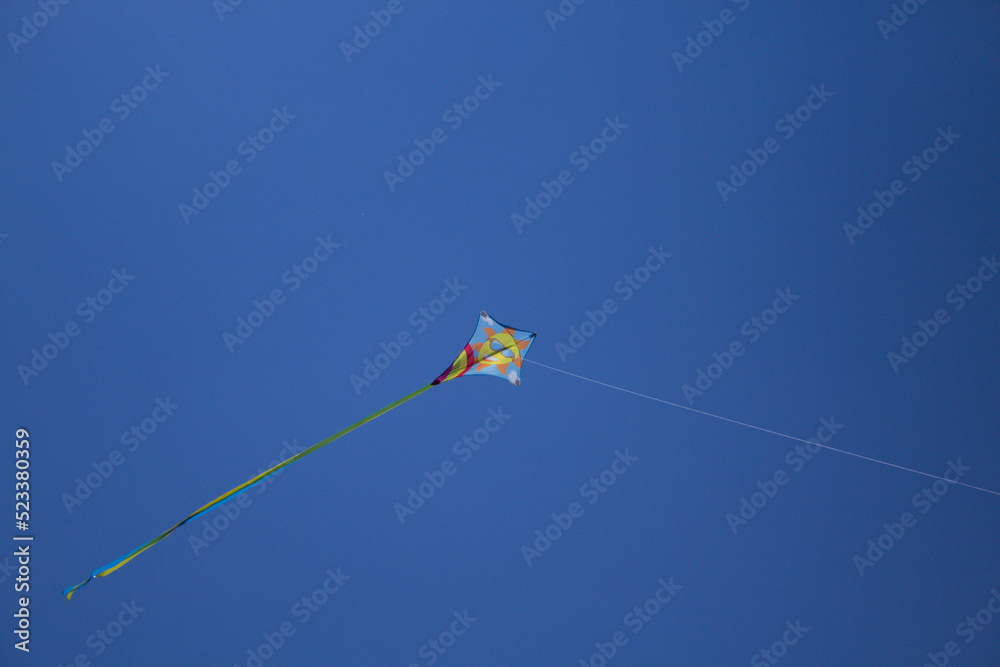 Image of a colorful kite flying high in the sky with a drawing of a ...