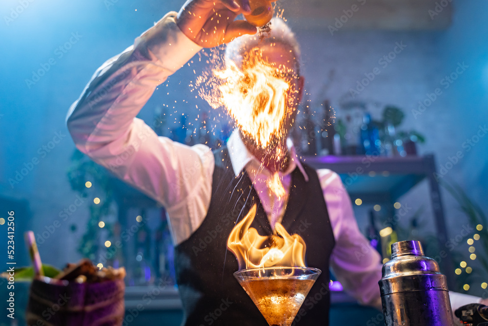 Foto de Bartender making a fire flame cocktail in a elegant night club ...