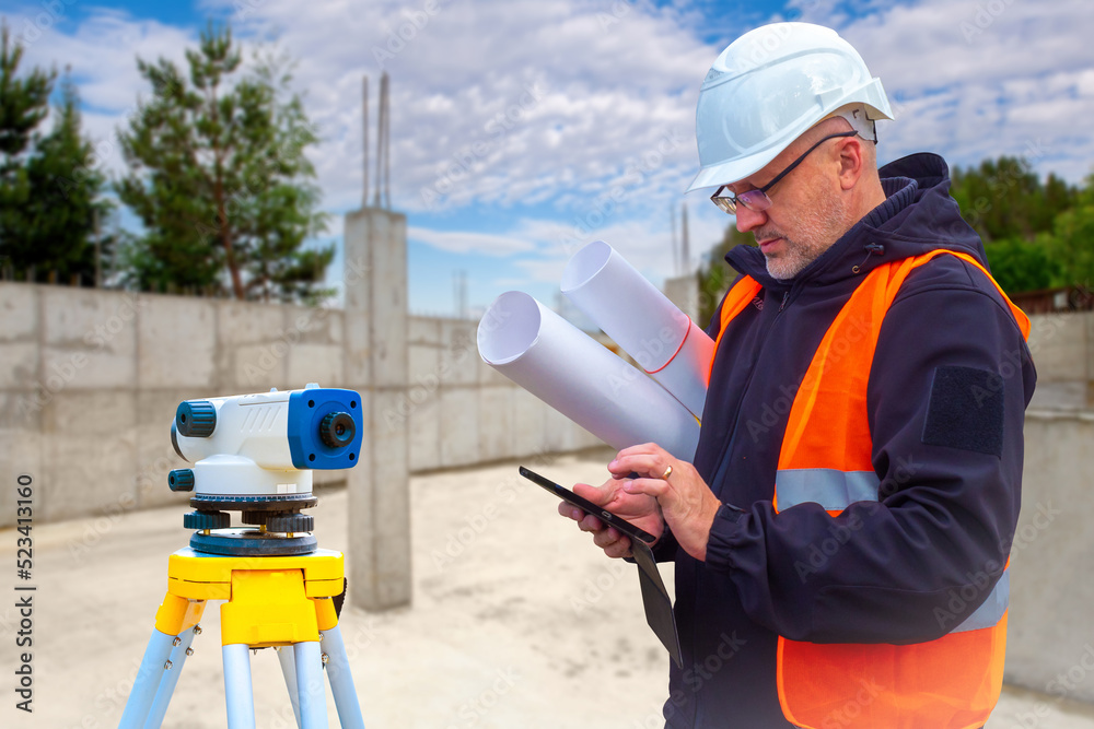 Man surveyor. Topographer is holding smartphone and bundle drawings ...