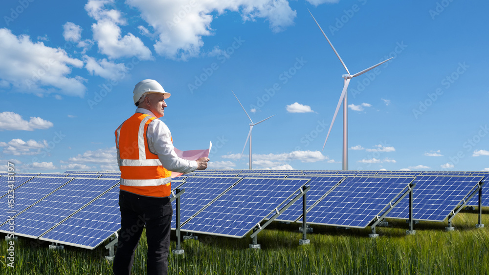 Solar and wind generators. ECO power plant architect. Man in field with ...