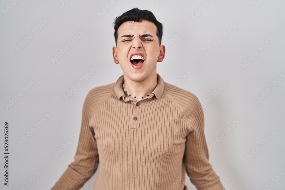 Non binary person standing over isolated background angry and mad ...