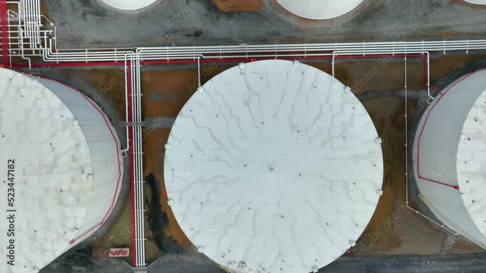 Top down aerial of oil gas bulk tanks at refinery. Pipeline connects ...