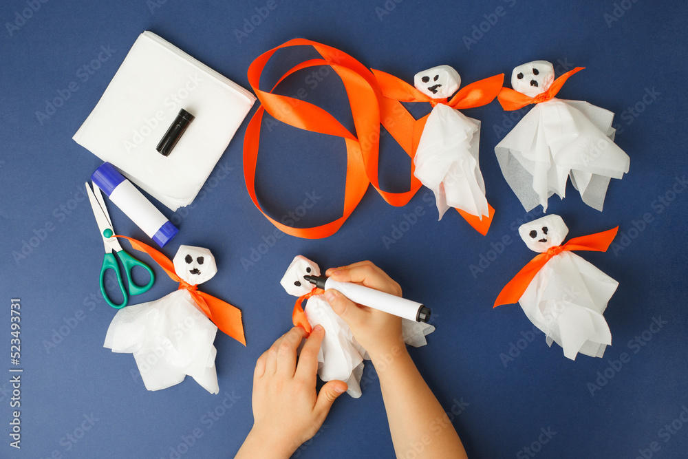 Boy makes Halloween toys ghost from white paper napkin. Creative DIY ...