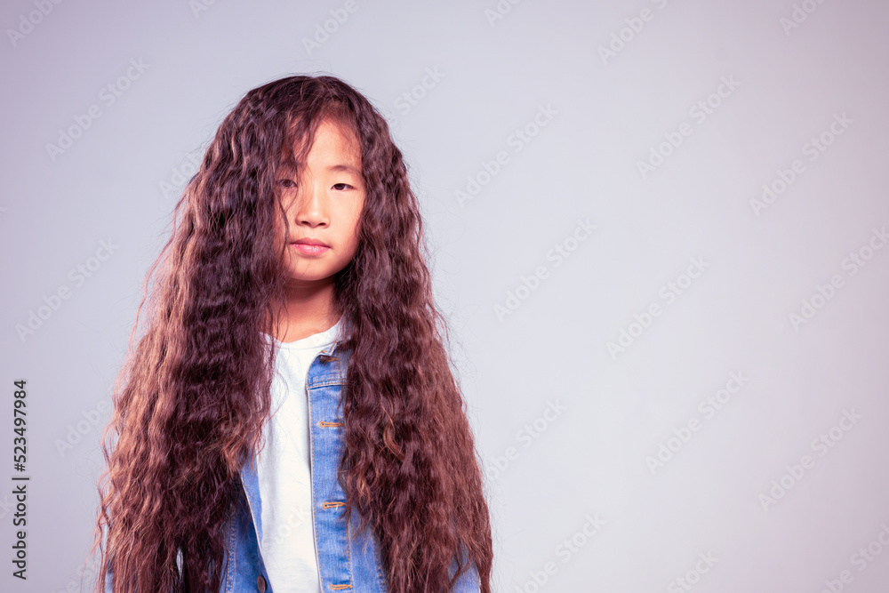 Hair covers face. Asian girl child with beautiful long curly hair. On a ...