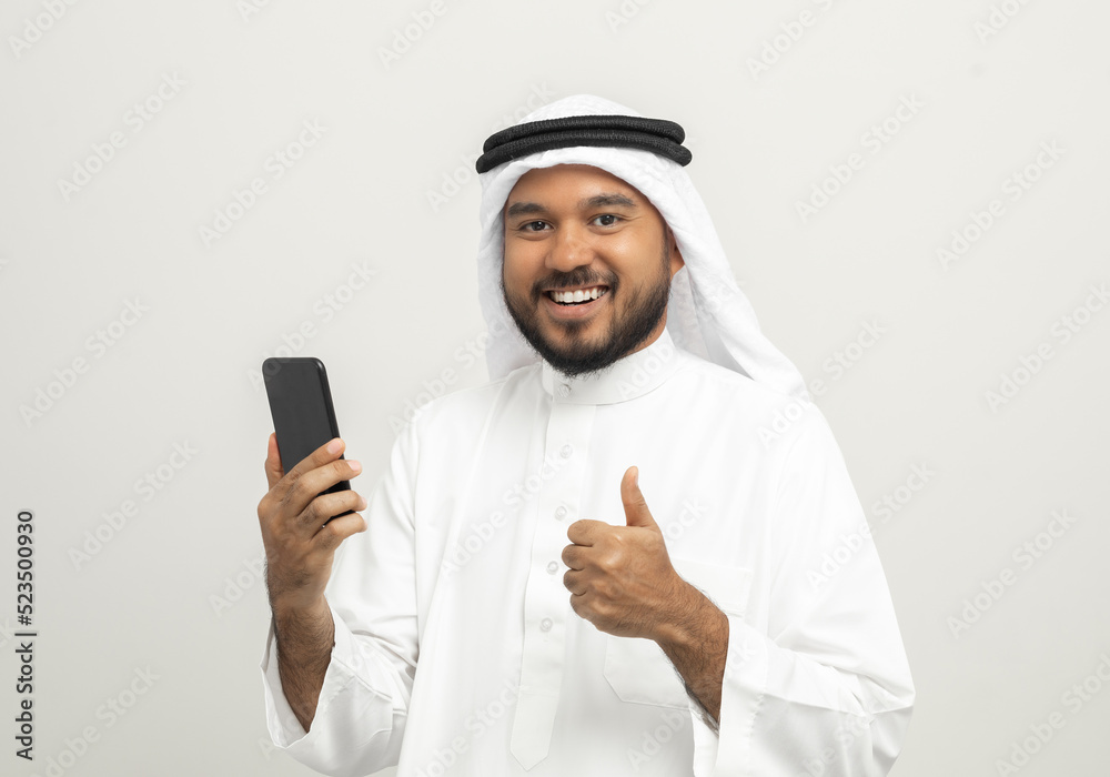 Portrait of arabic man with kandura dress using cellphone on isolated ...