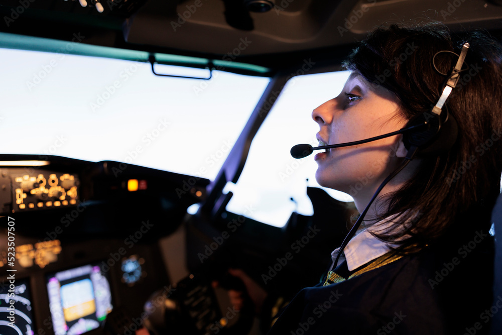 Female copilot flying plane from cockpit with dashboard command and ...