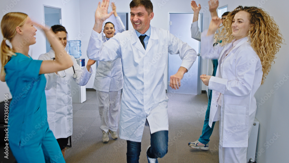 Smiling large group of nurses and doctors dancing excited in front of ...