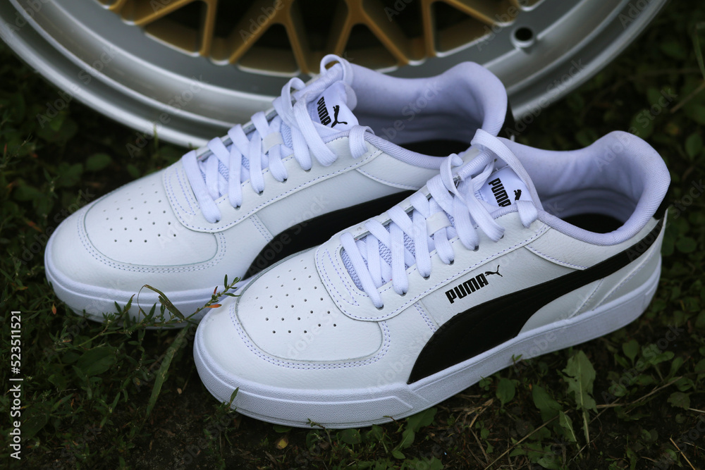 Stylish white Puma sneakers for men next to a classic car rim. Stock ...