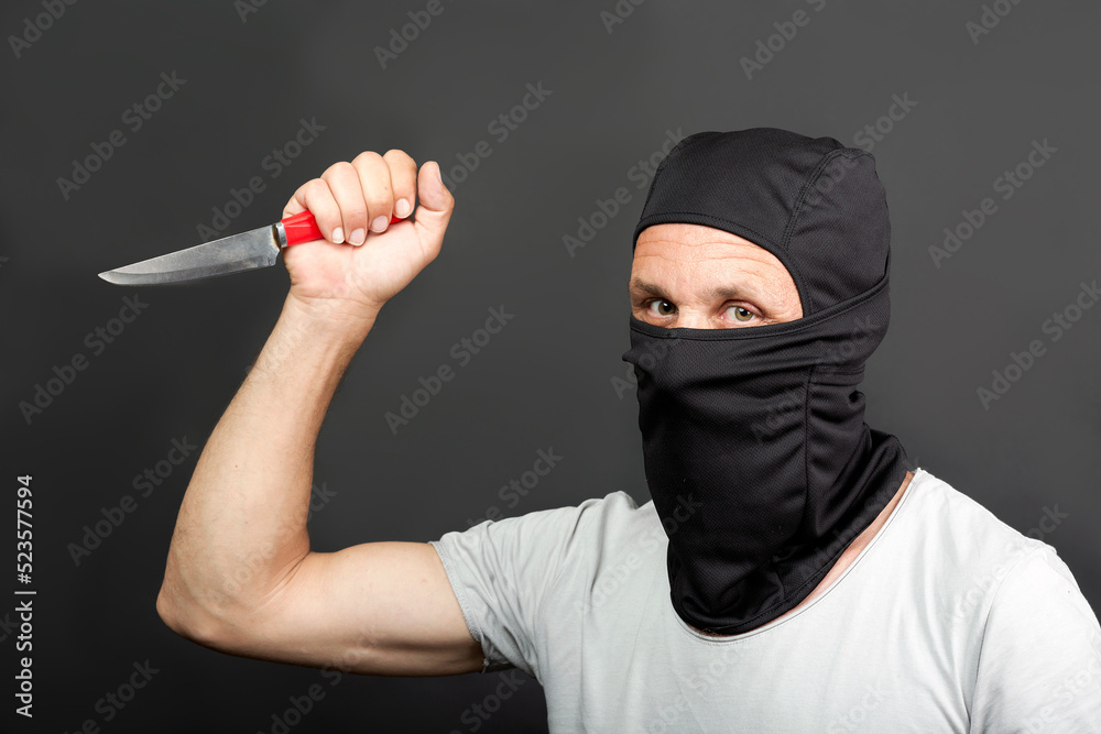 Man hidden in wearing black mask holding a pocket-knife and looking at ...