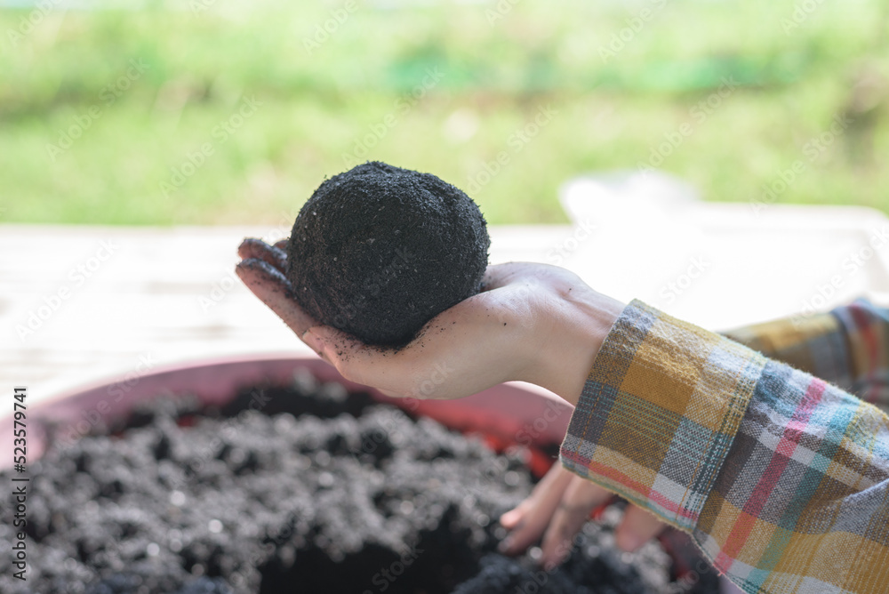 Unreconizable human hand holding round shape rice husk ash ball, making ...