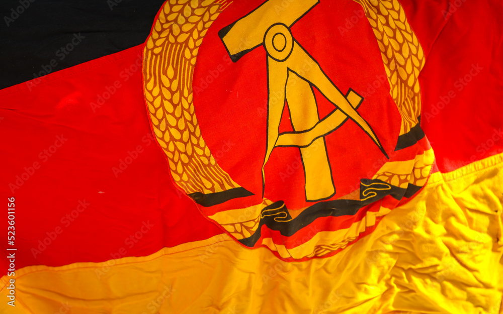 Foto de Ein Stück der Fahne der ehemaligen DDR mit Emblem, Hammer, Zirkel, Ährenkranz. do Stock ...