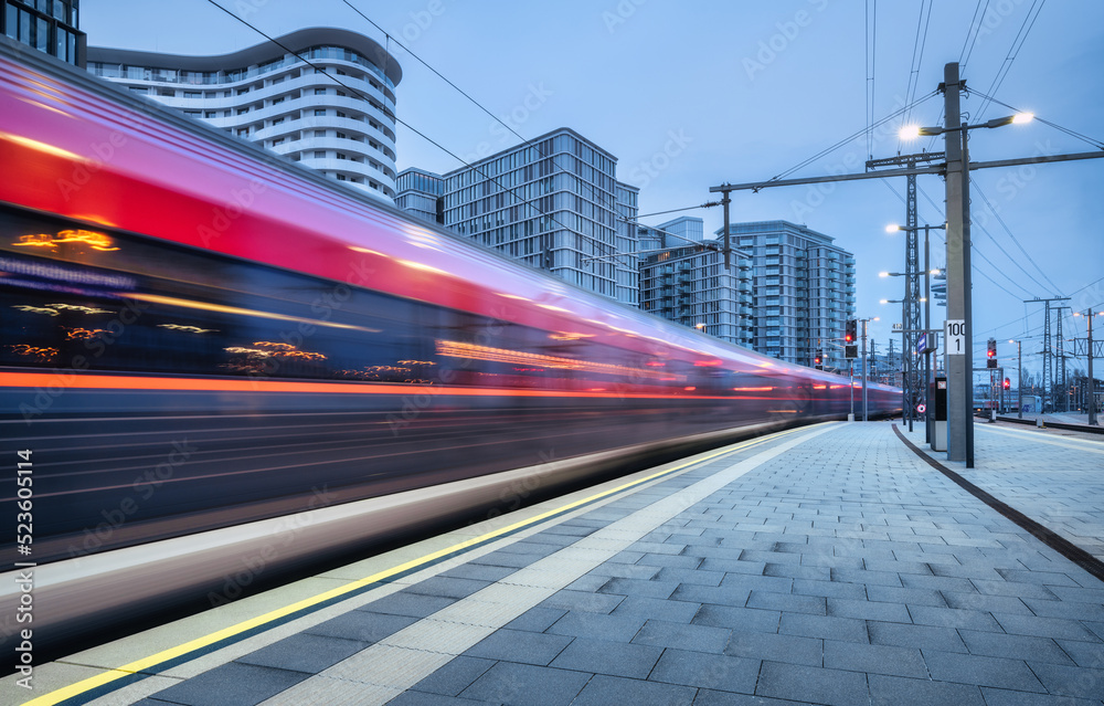 High speed train in motion on the railway station at sunset. Moving red ...