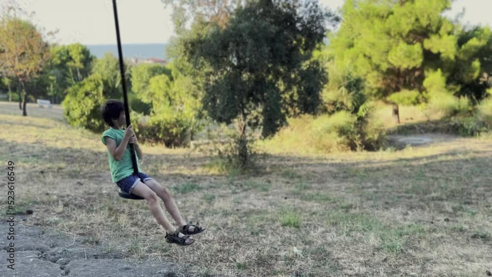 Happy school age boy rides on Flying Fox play equipment in a park ...