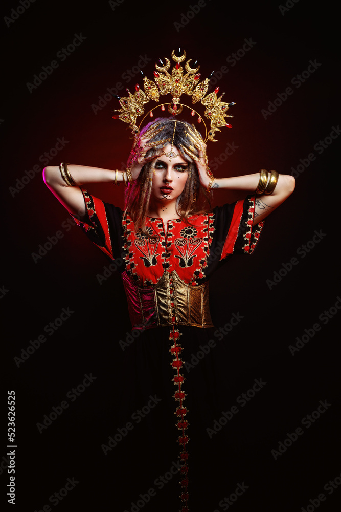 Pretty young ethnic priestess wearing gold crown and dreadlocks with ...