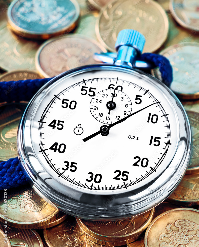 Analog stopwatch and pile of gold coins on a black background close-up ...