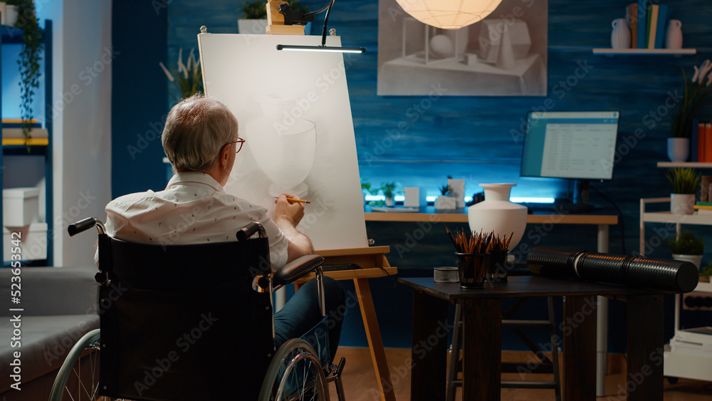 Senior adult with chronic impairment using pencils to draw vase model ...