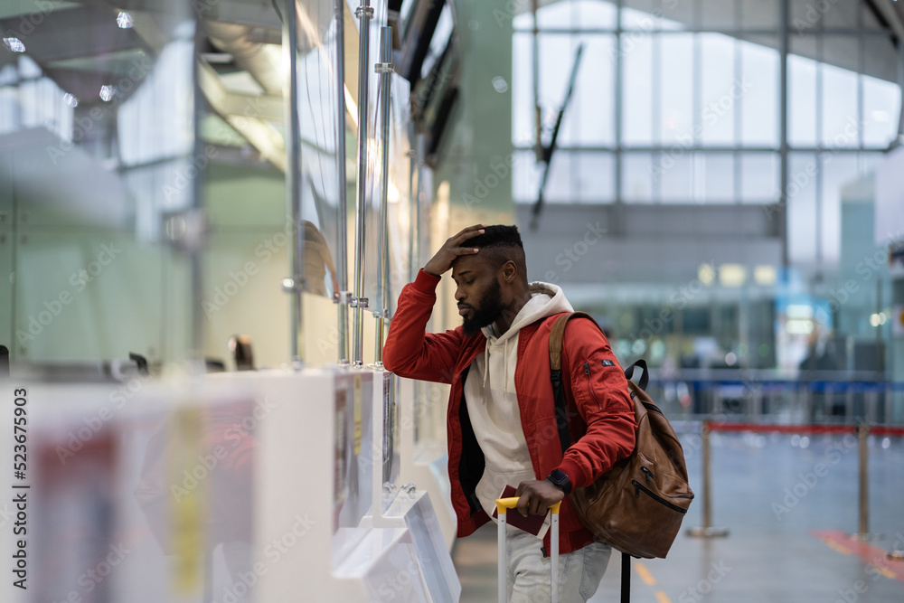Foto de Sad African guy traveler with luggage in airport terminal ...