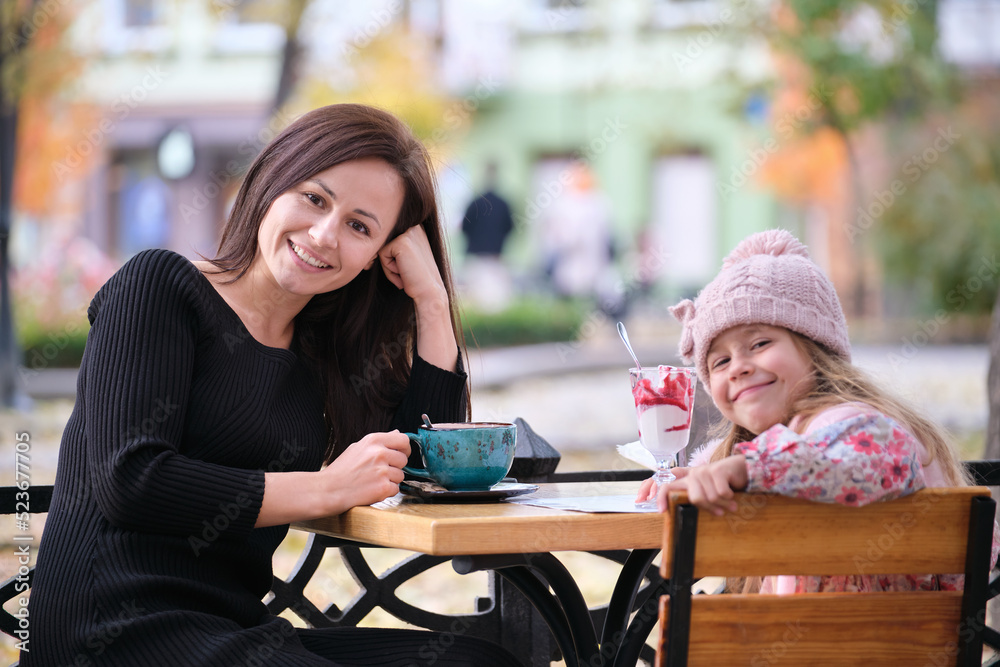 Young pretty woman having good time with her child daughter sitting at ...