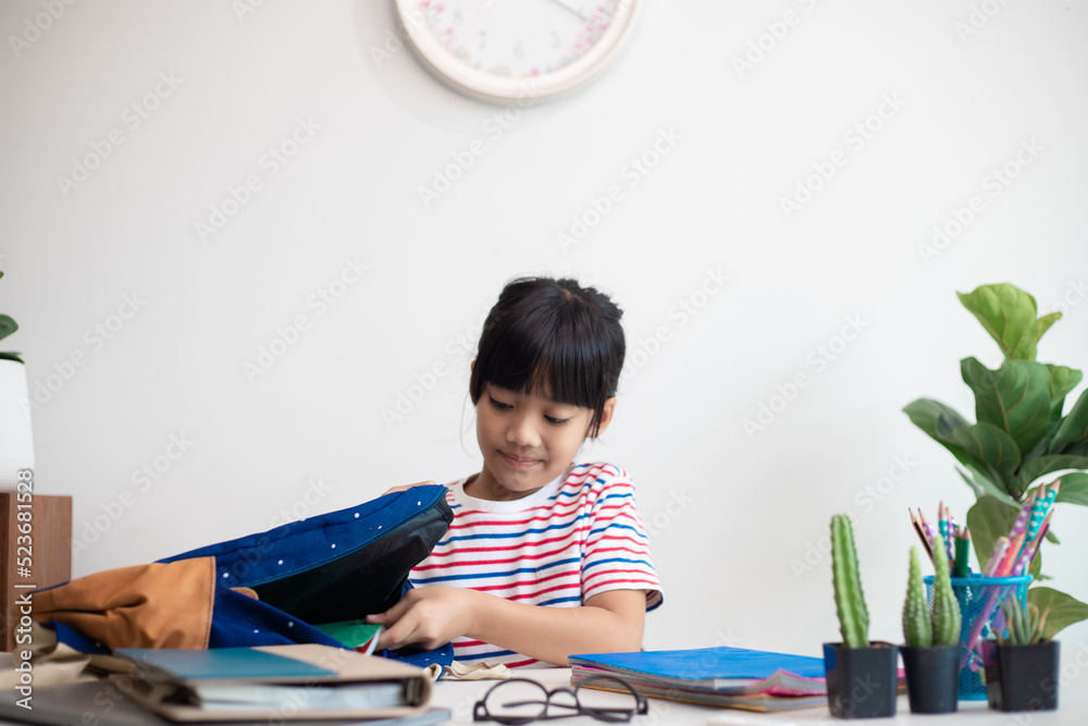 Asian cute primary school girls packing their school bags, preparing ...