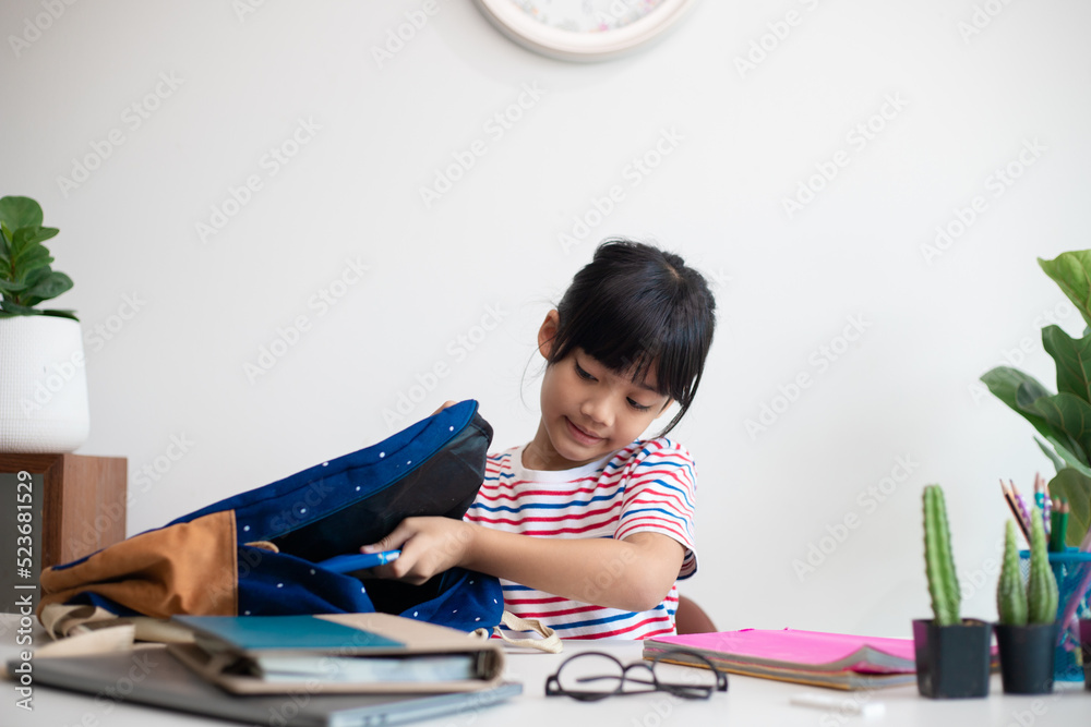 Asian cute primary school girls packing their school bags, preparing ...