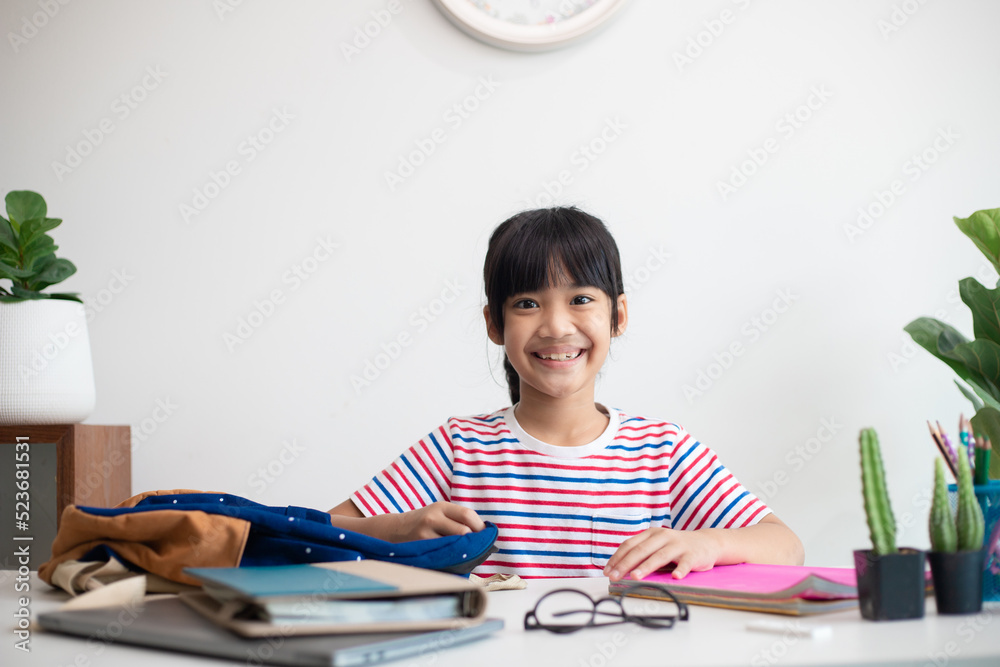 Asian cute primary school girls packing their school bags, preparing ...