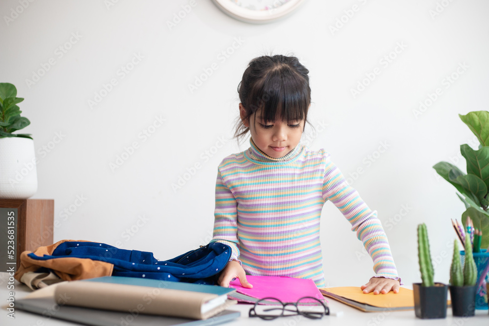 Asian cute primary school girls packing their school bags, preparing ...