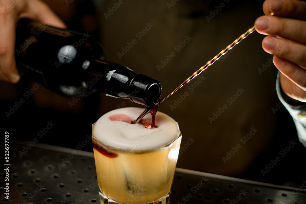 process of pouring syrup from bottle into glass with foamy cocktail ...