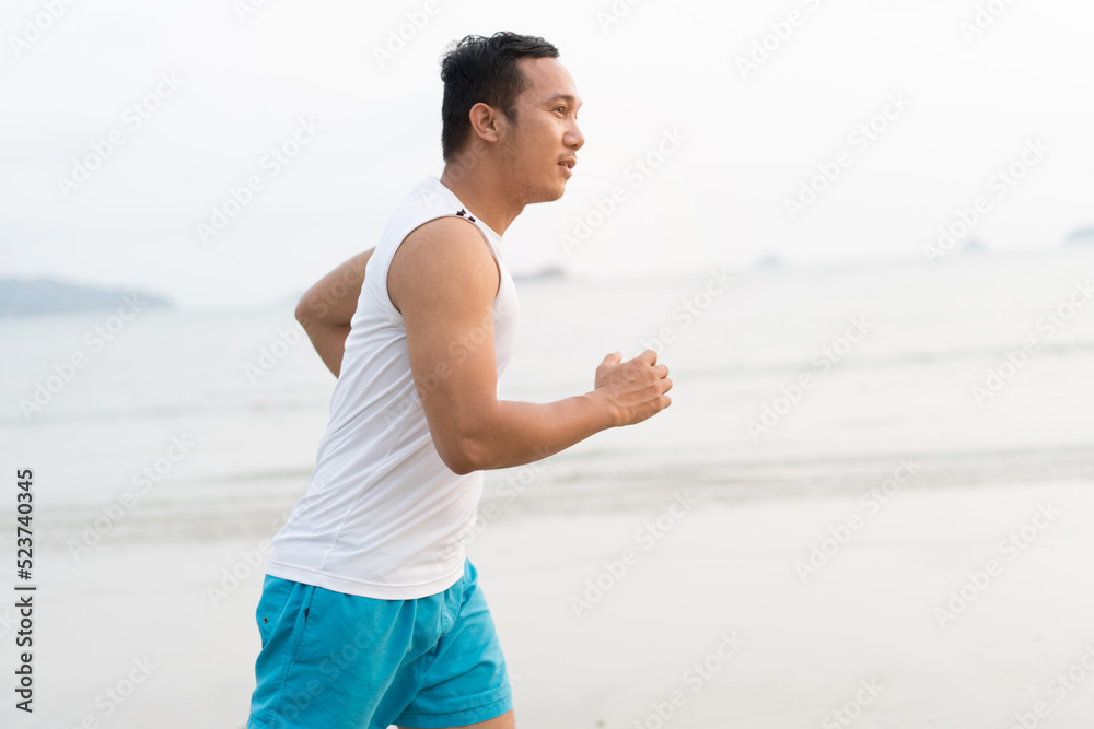 asian sport man running along seaside. running on beach with healthy ...