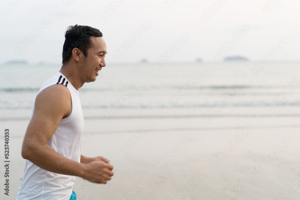 asian sport man running along seaside. running on beach with healthy ...