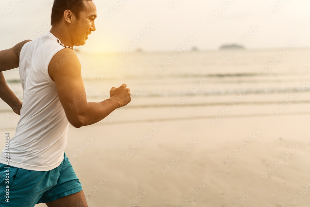 asian sport man running along seaside. running on beach with healthy ...
