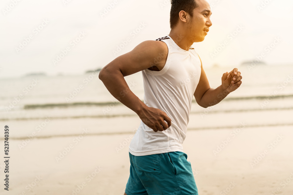asian sport man running along seaside. running on beach with healthy ...