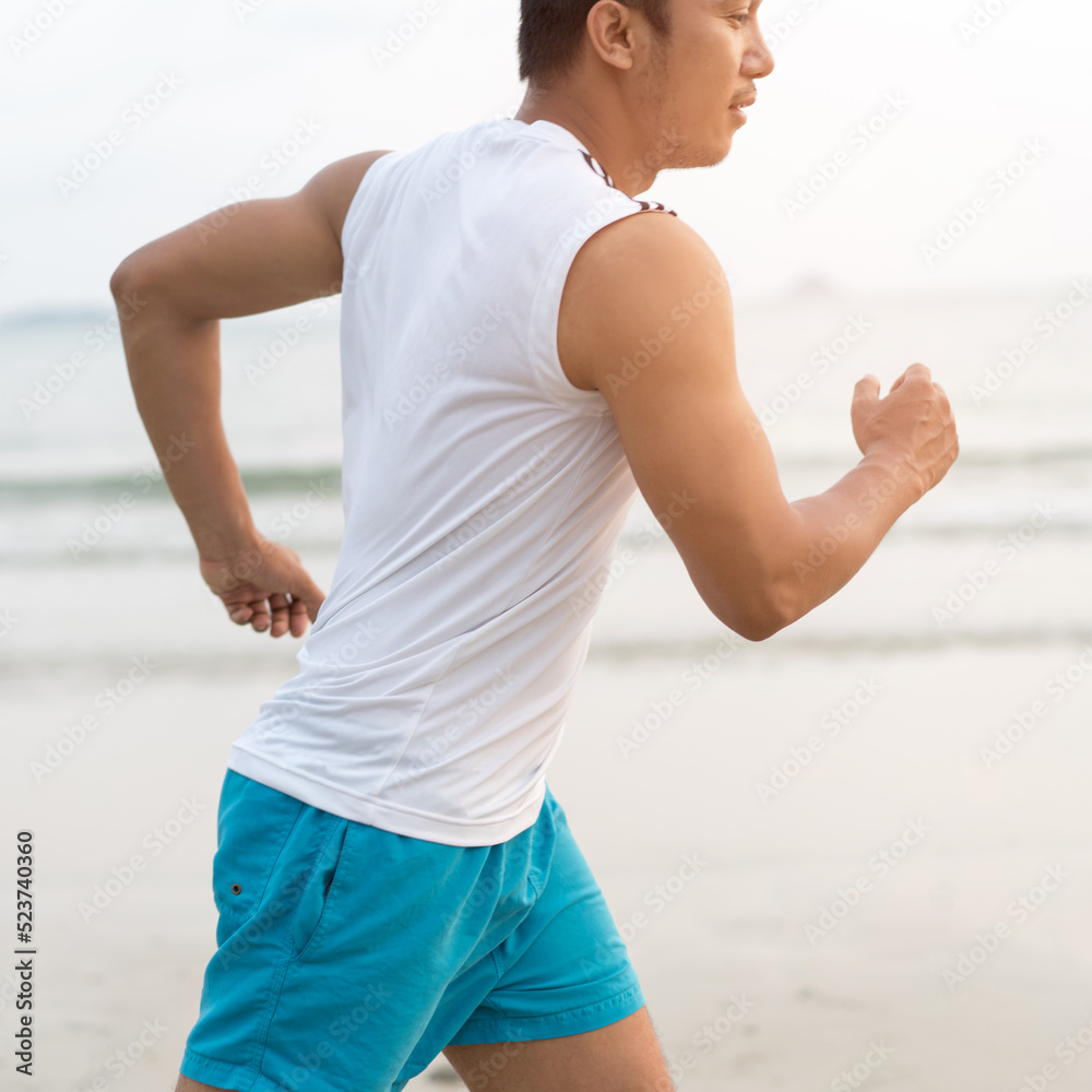 asian sport man running along seaside. running on beach with healthy ...