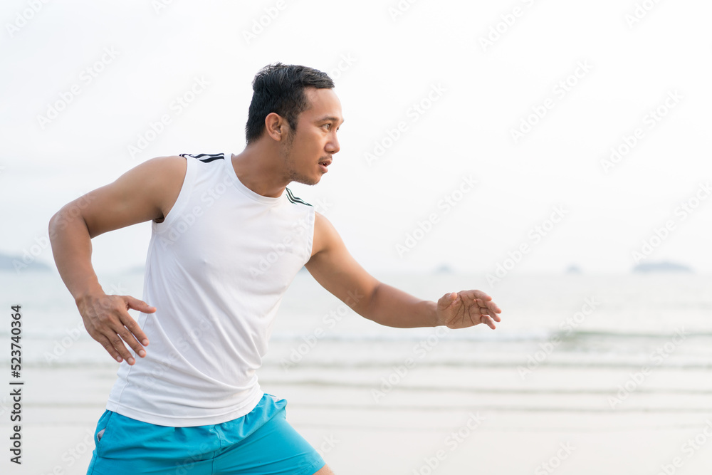 asian sport man running along seaside. running on beach with healthy ...