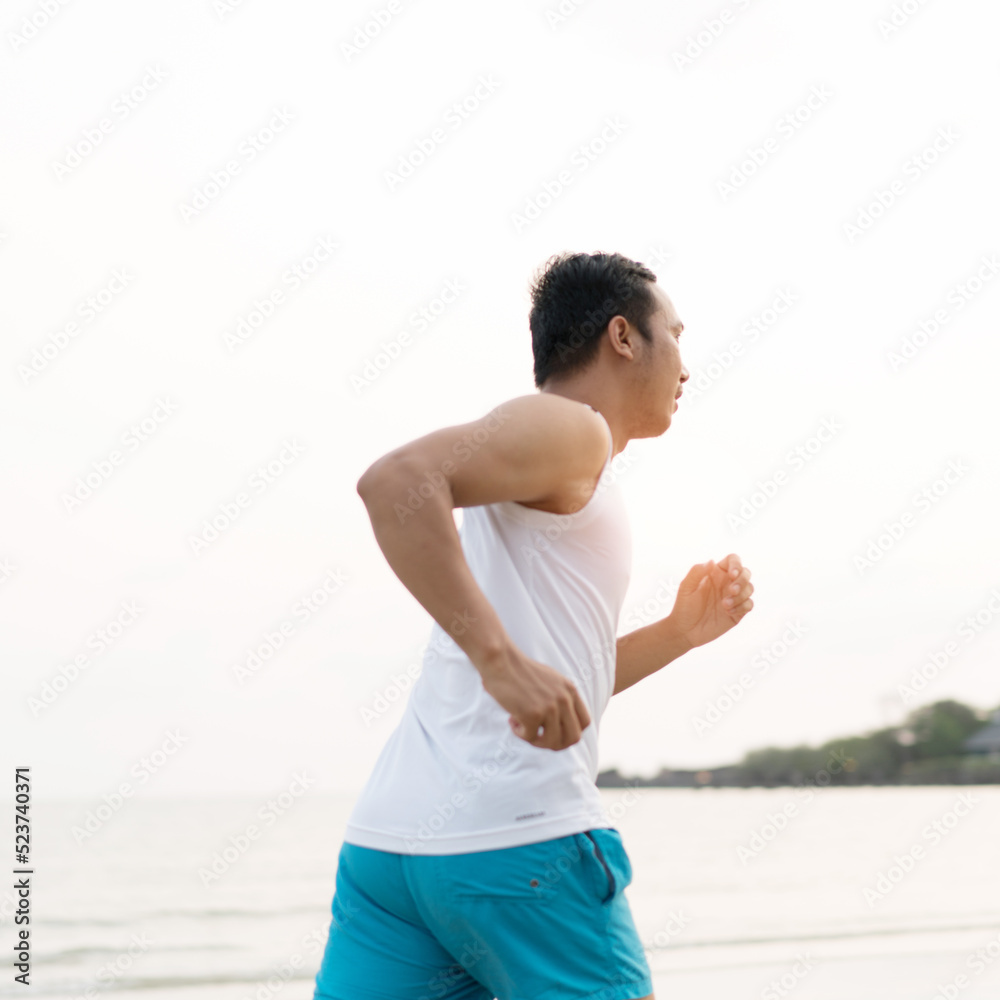 asian sport man running along seaside. running on beach with healthy ...