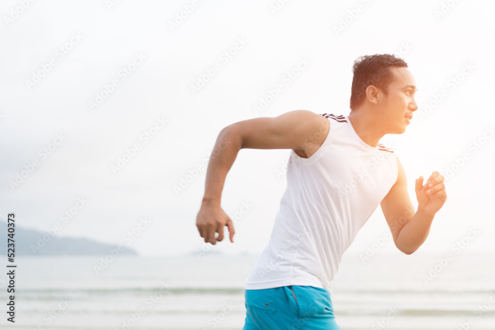 asian sport man running along seaside. running on beach with healthy ...