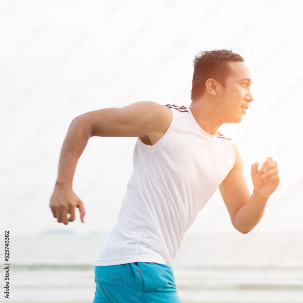 asian sport man running along seaside. running on beach with healthy ...